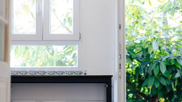 Um quarto com janela, porta e uma pequena mesa.