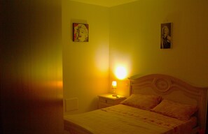 Um quarto com uma cama, uma mesa de cabeceira, uma luminária e dois quadros na parede.