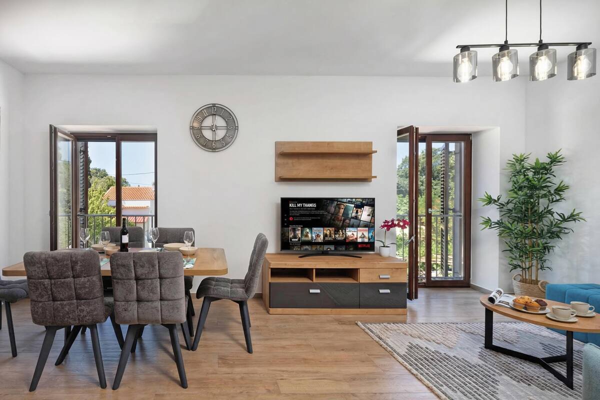 Uma sala de estar moderna com área de jantar, televisão de tela plana e uma janela grande.