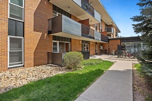 Um edifício residencial de vários andares com fachada de tijolos, varandas e um calçada pavimentada.