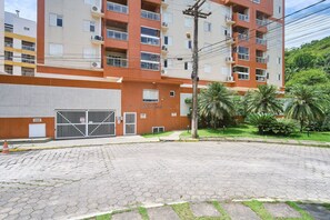 Um edifício de vários andares com fachada de tijolos, várias varandas e uma entrada com portão.