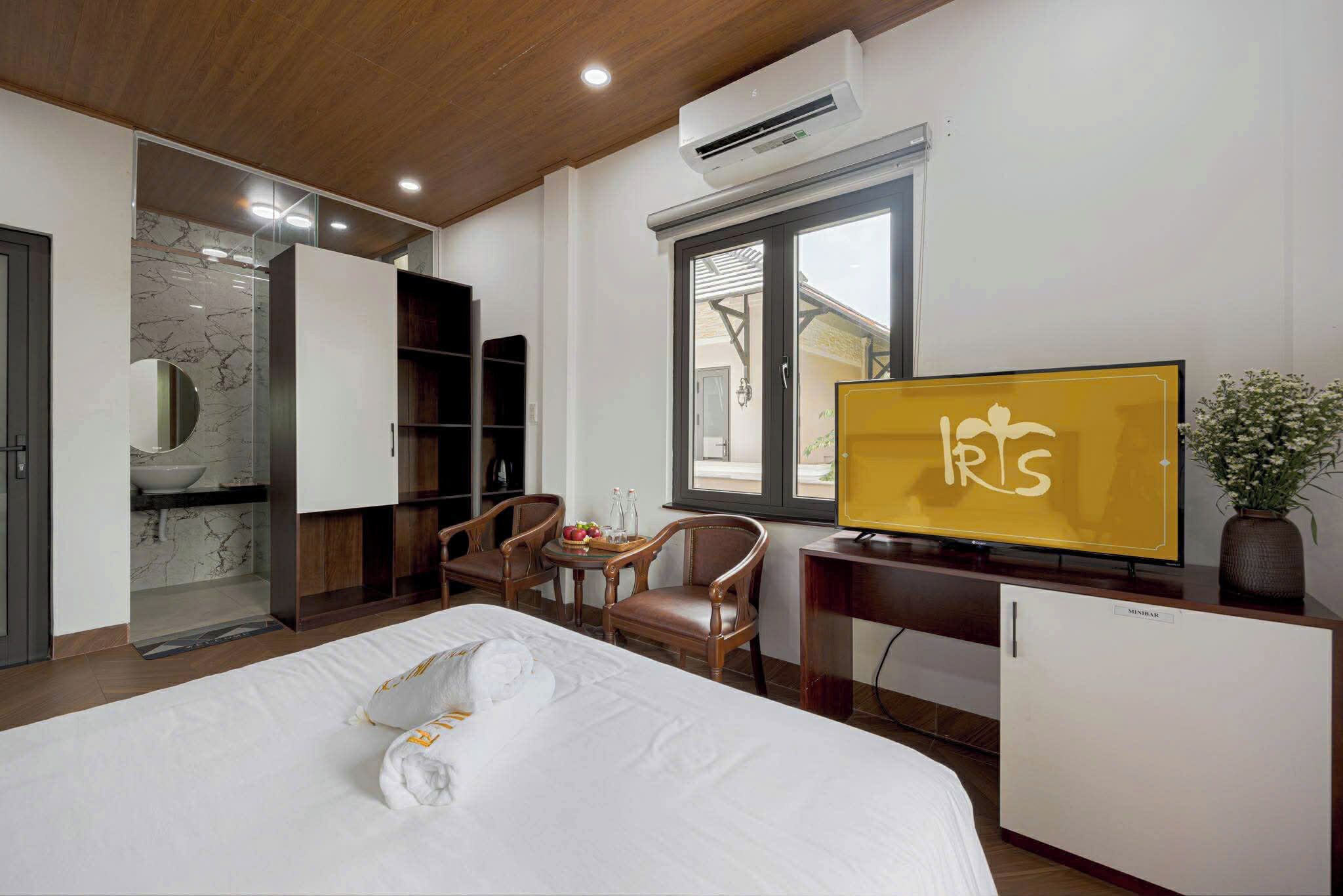 Quarto de hotel com cama, escrivaninha, cadeira, guarda-roupa e televisão.