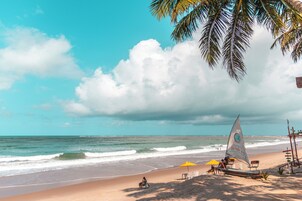 Uma cena de praia com barco, cadeiras e guarda-sóis.