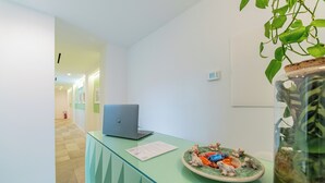 Um balcão de atendimento com um laptop, um prato de pequenas figuras e uma planta em vaso.