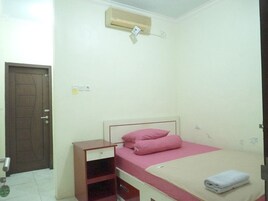 Um quarto com cama, mesa de cabeceira, guarda-roupa e uma porta.