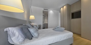 Um quarto moderno com uma cama grande, mesas de cabeceira, uma escrivaninha e uma cadeira.