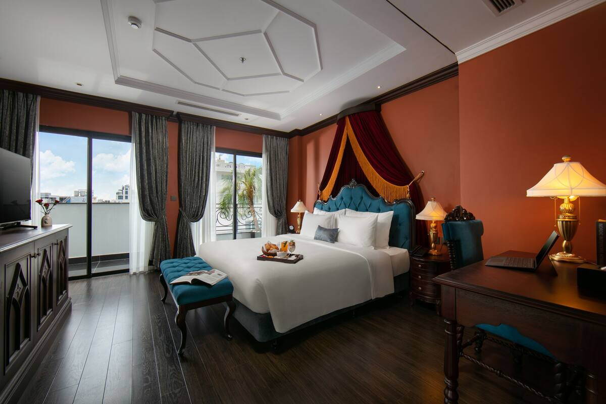 Quarto de hotel com uma cama grande, uma escrivaninha e vista para a cidade.