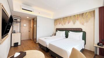 Quarto de hotel com duas camas, televisão, secretária e espelho.