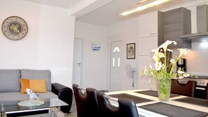 Uma sala de estar moderna com um sofá, uma mesa de jantar e uma área de cozinha com fogão e micro-ondas.