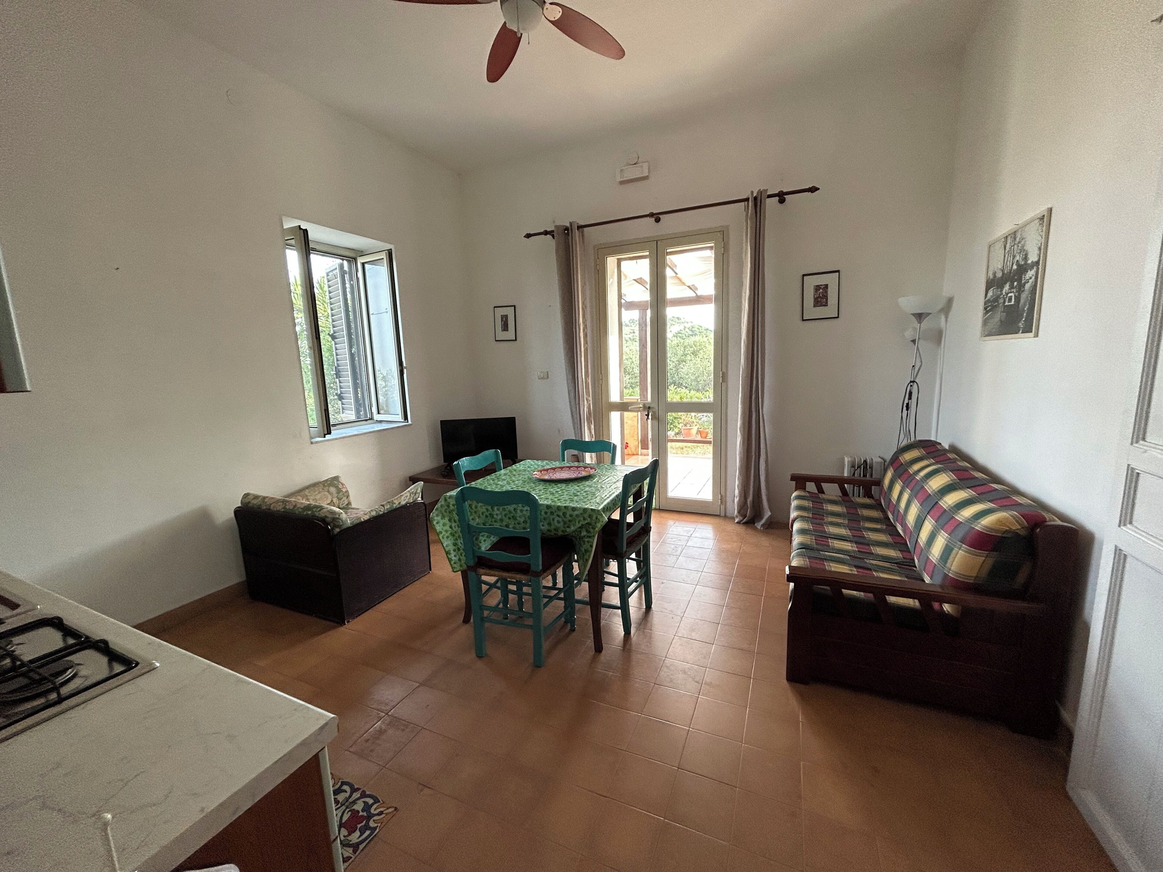 Um espaço compacto com área de refeições, sofá, televisão e cozinha.