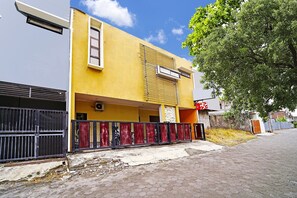 Um edifício amarelo com um portão vermelho, um relógio e uma placa com a inscrição 'Casa'.