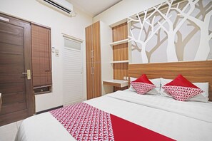 Quarto de hotel com uma cama, guarda-roupa, espelho e parede com design de árvore.