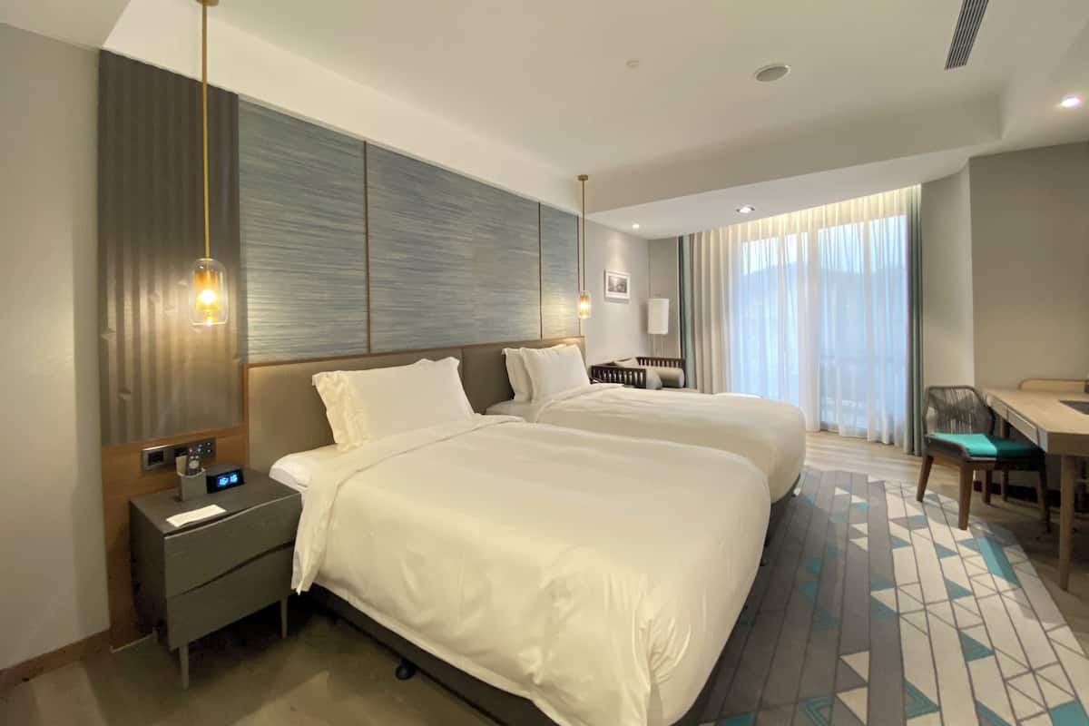 Quarto de hotel moderno com uma cama grande, mesas de cabeceira, uma escrivaninha e uma cadeira.