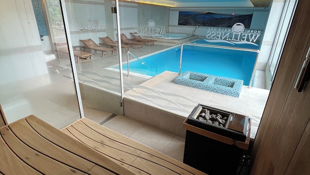 Quarto de hotel moderno com parede de vidro com vista para uma piscina e área de lazer.