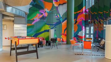 Um espaço interior moderno com mesa de futebol, arte abstrata colorida e assentos contemporâneos.