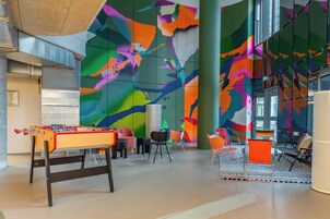 Um espaço interior moderno com mesa de futebol, arte abstrata colorida e assentos contemporâneos.