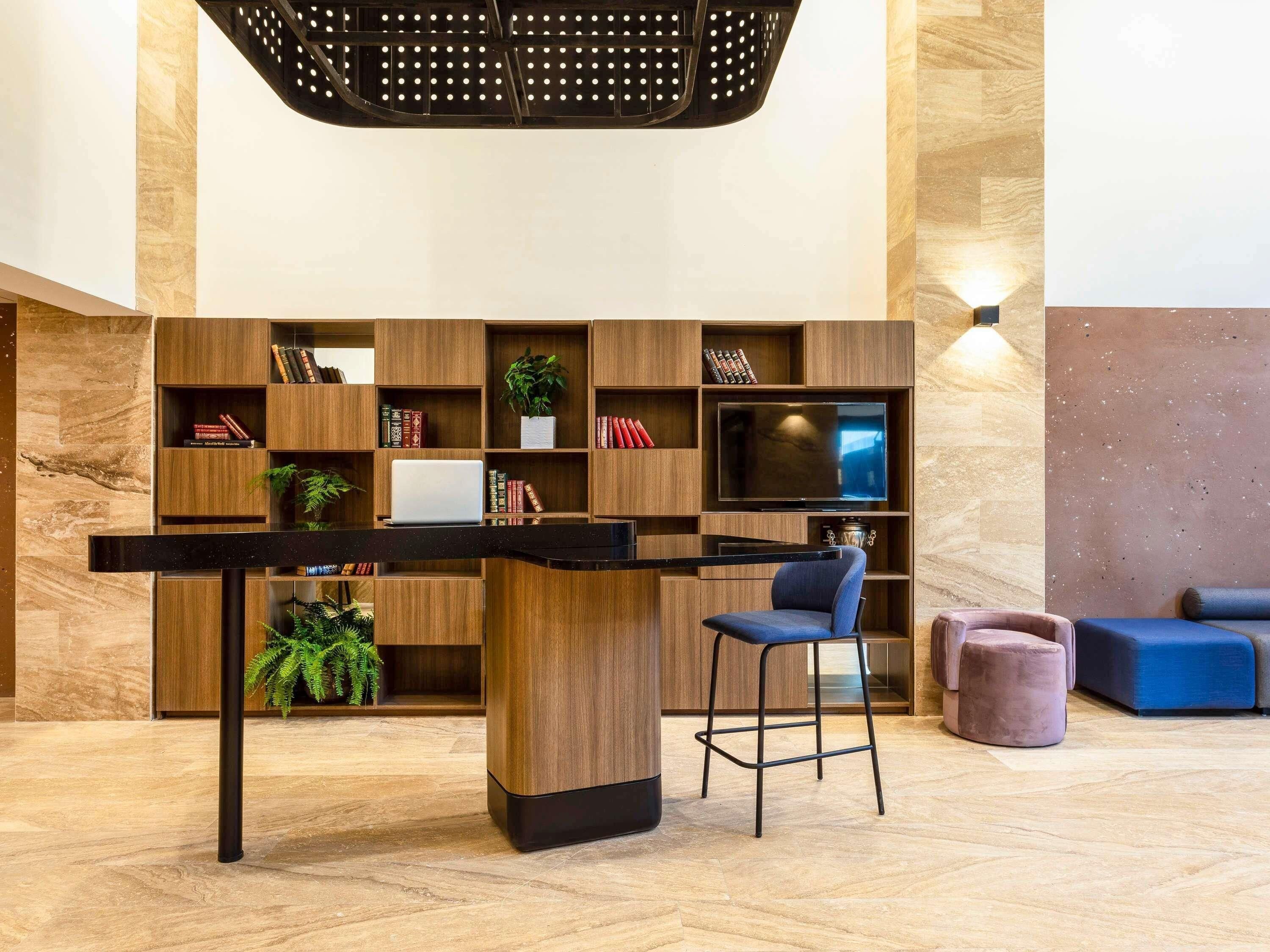 Um lobby moderno com área de bar, assentos e televisão.
