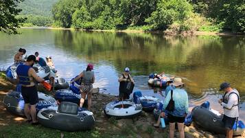 Um grupo de pessoas se preparando para uma aventura de rafting em um rio calmo, cercado por vegetação exuberante.