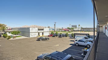 Um estacionamento com vários carros, um edifício com telhado plano e um céu azul claro.