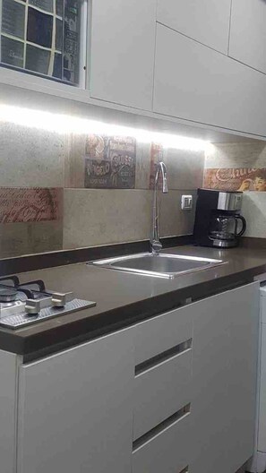 Cozinha com pia, cafeteira e armários.