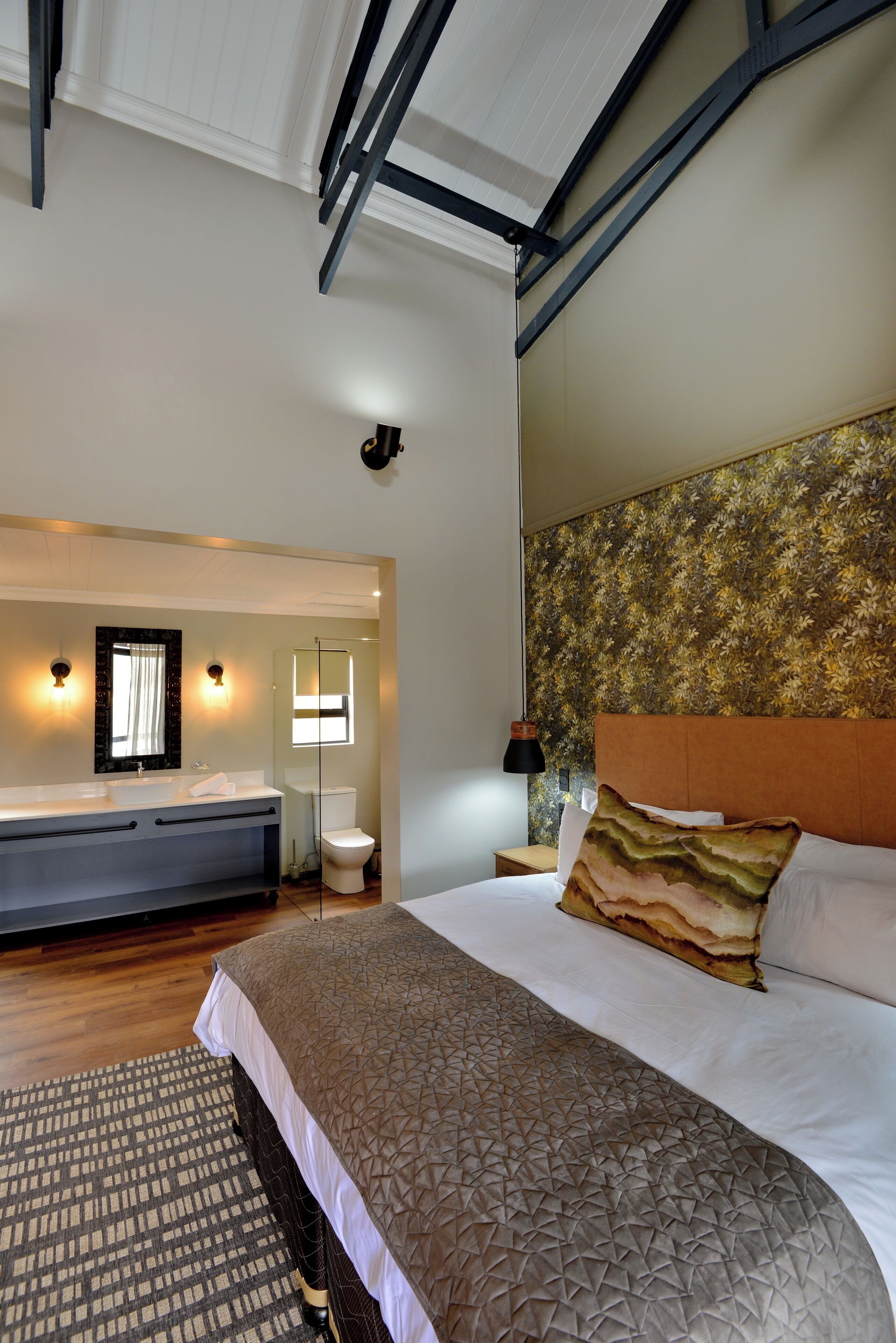 Quarto de hotel moderno com uma cama grande, banheiro com chuveiro e vista para o exterior.