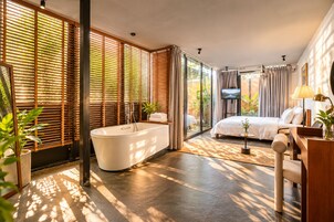 Quarto moderno com banheira, cama e televisão.