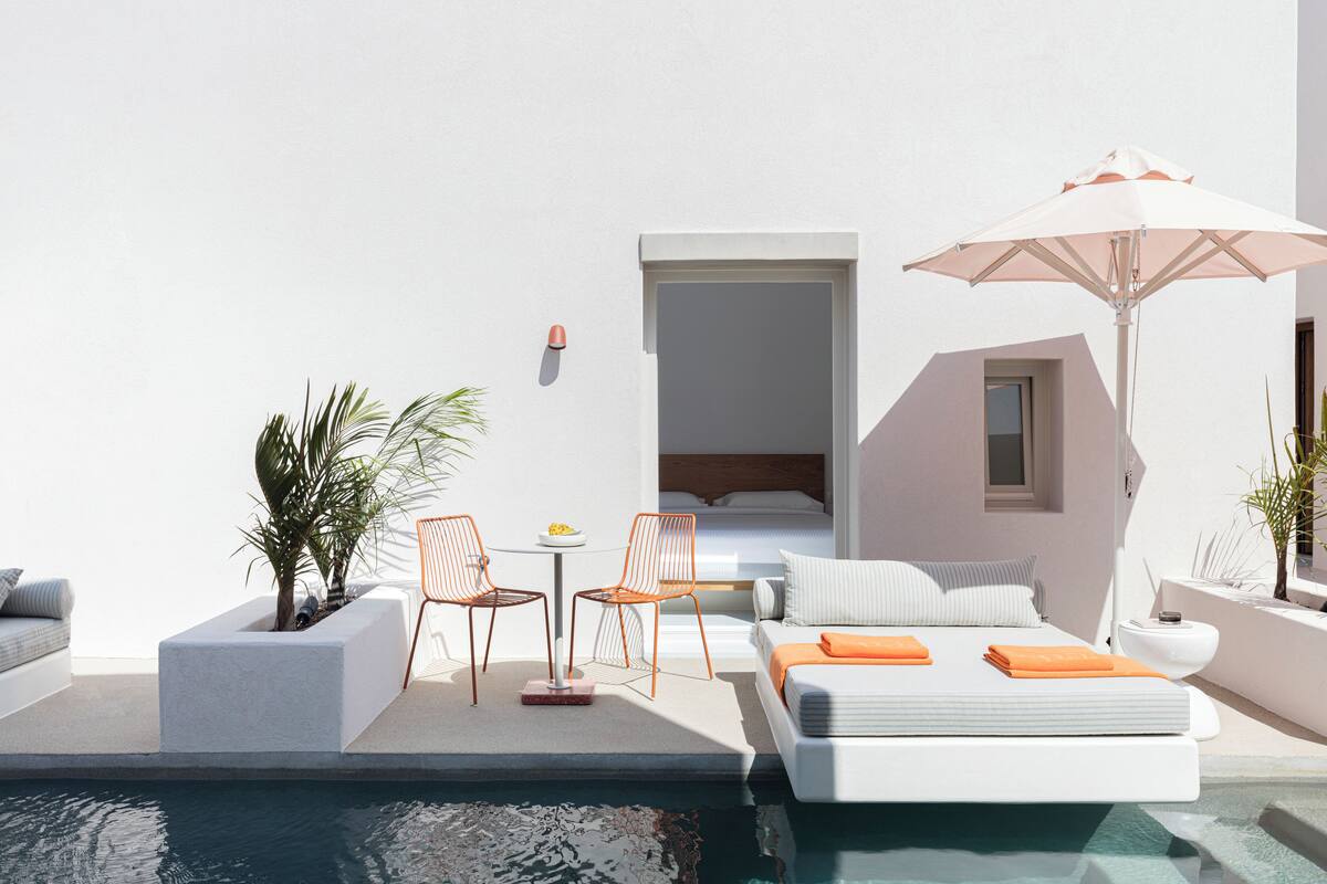 Uma área moderna com piscina ao ar livre, incluindo um sofá, duas cadeiras, uma mesinha e um grande guarda-sol.