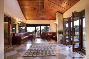 Um hall amplo com piso xadrez, assentos de couro e teto de madeira.