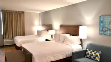 Quarto de hotel com duas camas, um sofá e uma obra de arte na parede.