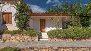 Uma trilha de pedras leva a uma casa com porta de madeira e degraus.