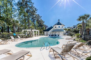 Piscina com espreguiçadeiras e um gazebo, cercada por árvores e um edifício com cúpula.