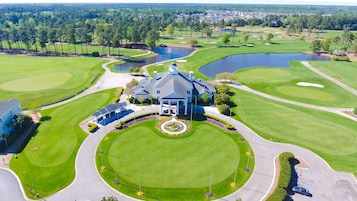 Um campo de golfe com clube, lago e relvado bem cuidado.