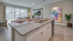 Uma cozinha moderna com bancadas de granito, máquina de lavar louça embutida e área de jantar com mesa e cadeiras.