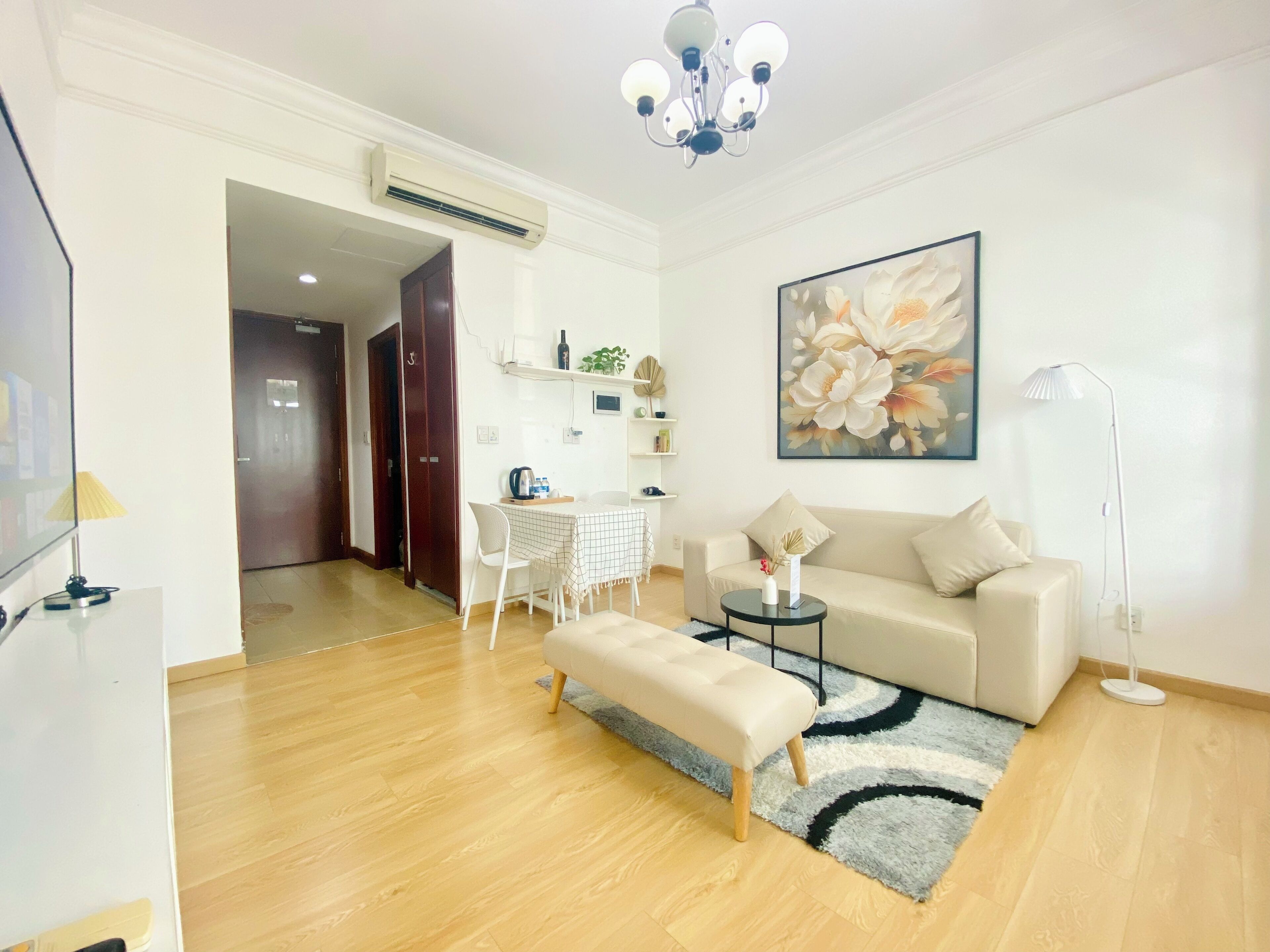 Uma sala moderna com um sofá, uma mesa de jantar e um banquinho. Há um quadro na parede e um abajur.