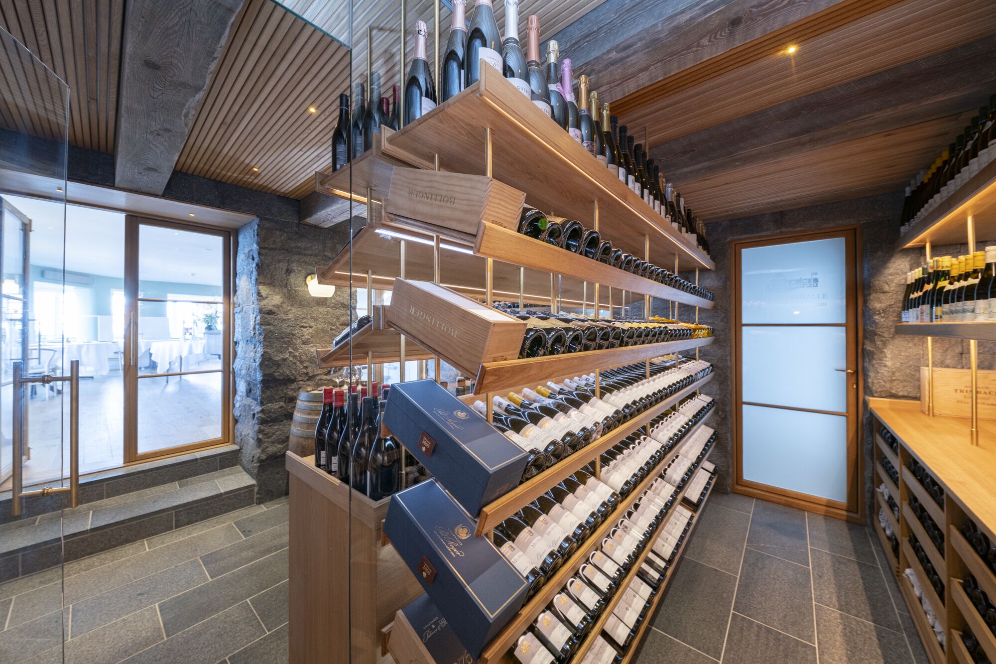Uma adega com prateleiras e racks de madeira contendo diversas garrafas de vinho.