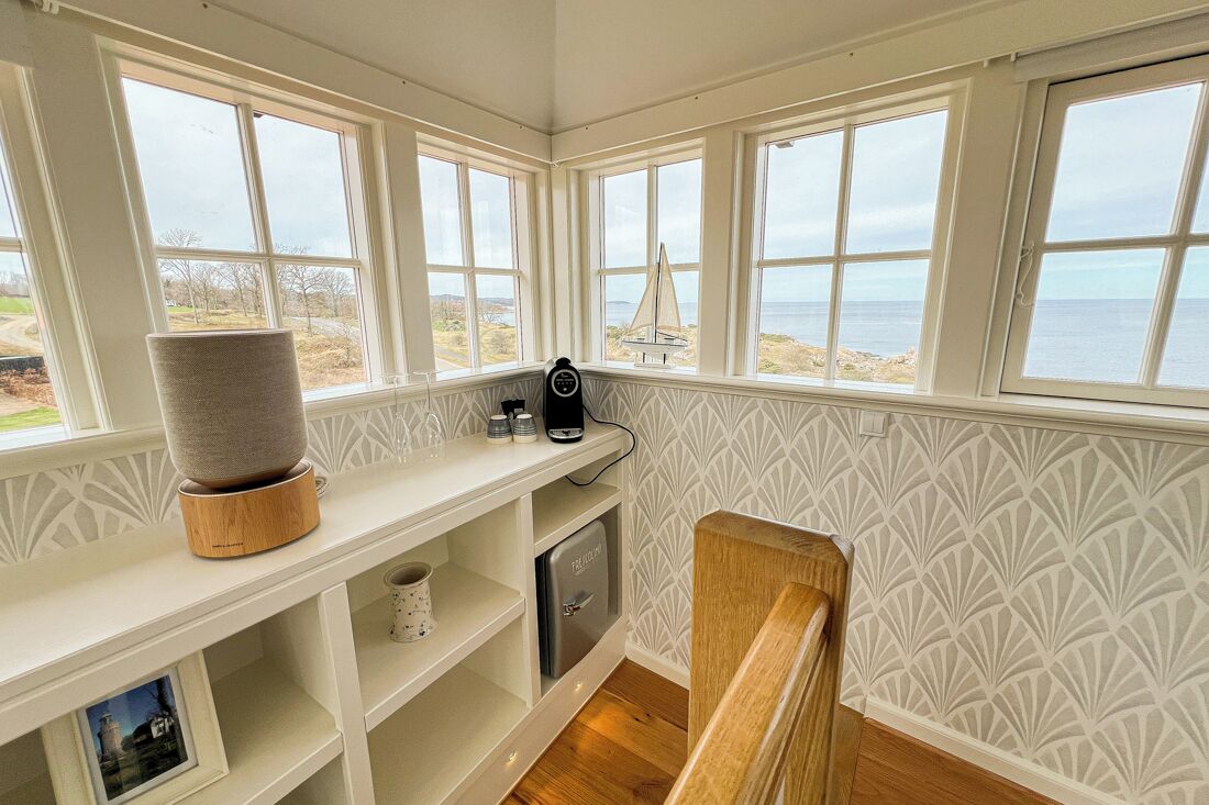 Quarto com vista para o mar, um banco de madeira, uma prateleira com uma chaleira e um quadro emoldurado.