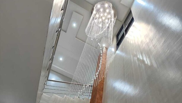 Um interior moderno com teto alto, uma coluna central e um lustre pendurado.