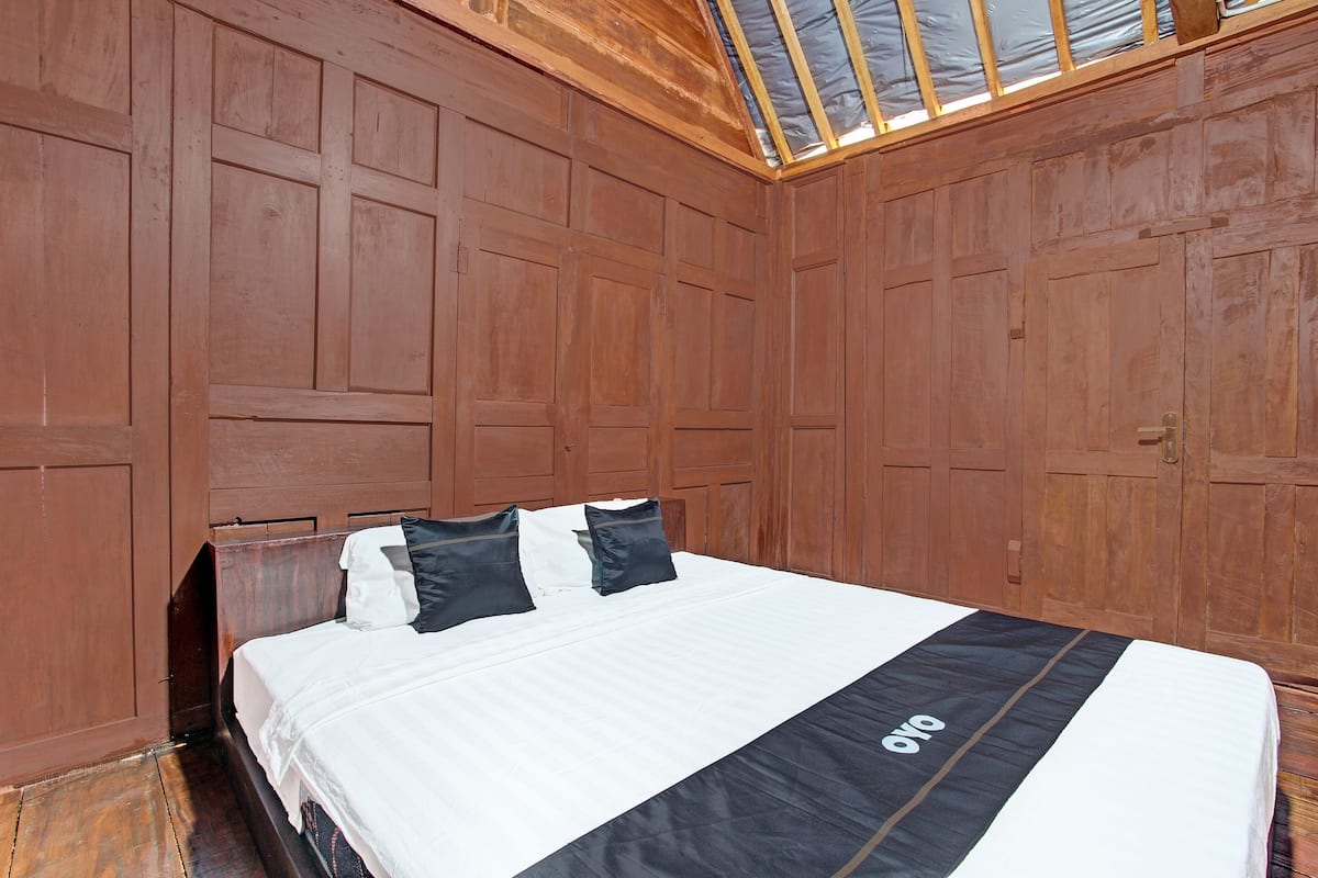 Quarto com painéis de madeira, uma cama, um claraboia e uma porta.