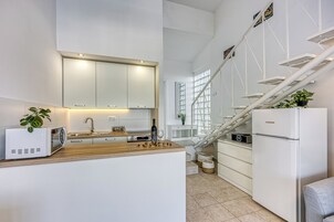 Uma cozinha moderna com armários brancos, micro-ondas, pia e geladeira.