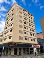 Edifício de hotel com vários andares, um letreiro com a inscrição 'ACOMODARE HOTEL' e uma vitrine com manequins.
