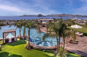 Uma área de piscina com deck de madeira, cadeiras de descanso e um bangalô.