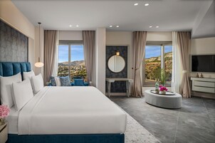 Quarto de hotel moderno com uma cama grande, um espelho redondo, uma TV e vista para a cidade.