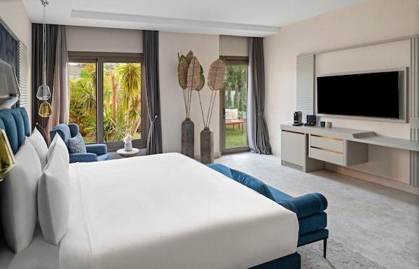 Quarto moderno com uma cama grande, uma escrivaninha com televisão e vista para o exterior.