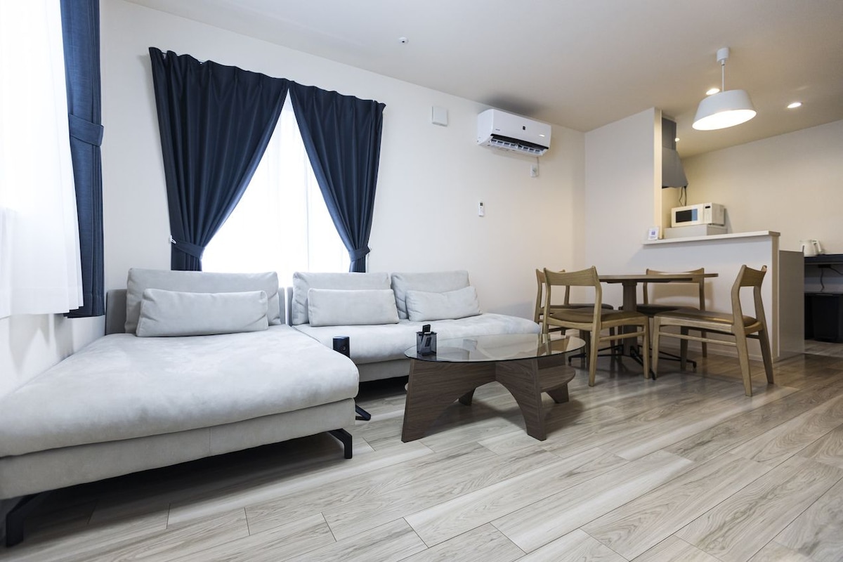 Uma sala de estar moderna com um sofá, uma mesa de centro e uma área de jantar com cadeiras.