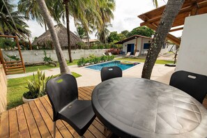 Um pátio externo com piscina, deck de madeira e área de estar.