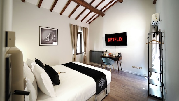 Quarto com cama, escrivaninha, cadeira, televisão e guarda-roupa.