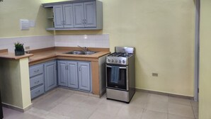 Cozinha compacta com armários cinza, uma pia de aço inoxidável e um fogão a gás Whirlpool.