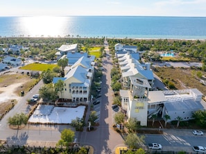 Vista aérea de um hotel à beira-mar com vários edifícios, um estacionamento e vista para o oceano.