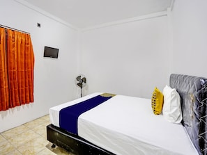Quarto de hotel com cama, ventoinha, televisão e cortinas laranja.