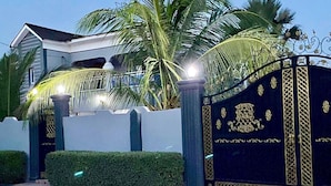 Portão fechado com uma palmeira e um edifício ao fundo.